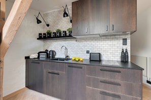 Uma cozinha moderna com armários de madeira escura, bancada preta e painel de backsplash de tijolos brancos.