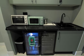 Uma cozinha compacta com micro-ondas, torradeira, pia e um pequeno frigorífico.