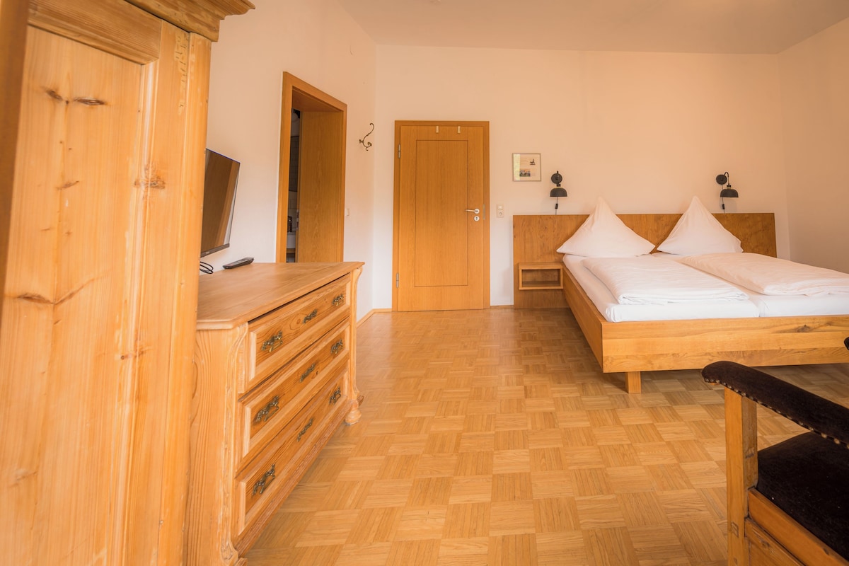Quarto com cama de madeira, penteadeira de madeira, guarda-roupa de madeira e um banco de madeira.