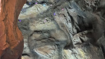 Uma banheira de hidromassagem em um ambiente que lembra uma caverna, com formações rochosas e uma estrutura de madeira.
