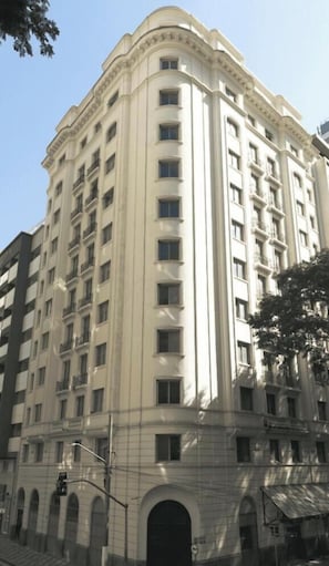 Um edifício de vários andares com arquitetura clássica, apresentando uma entrada central com abóbadas e fachada simétrica.