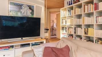 Sala de estar com televisão, estantes e sofá.