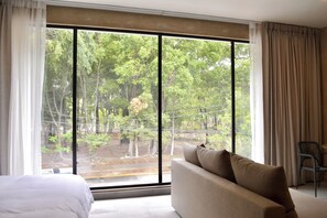 Um quarto com uma janela grande, um sofá, uma cadeira e uma cama.