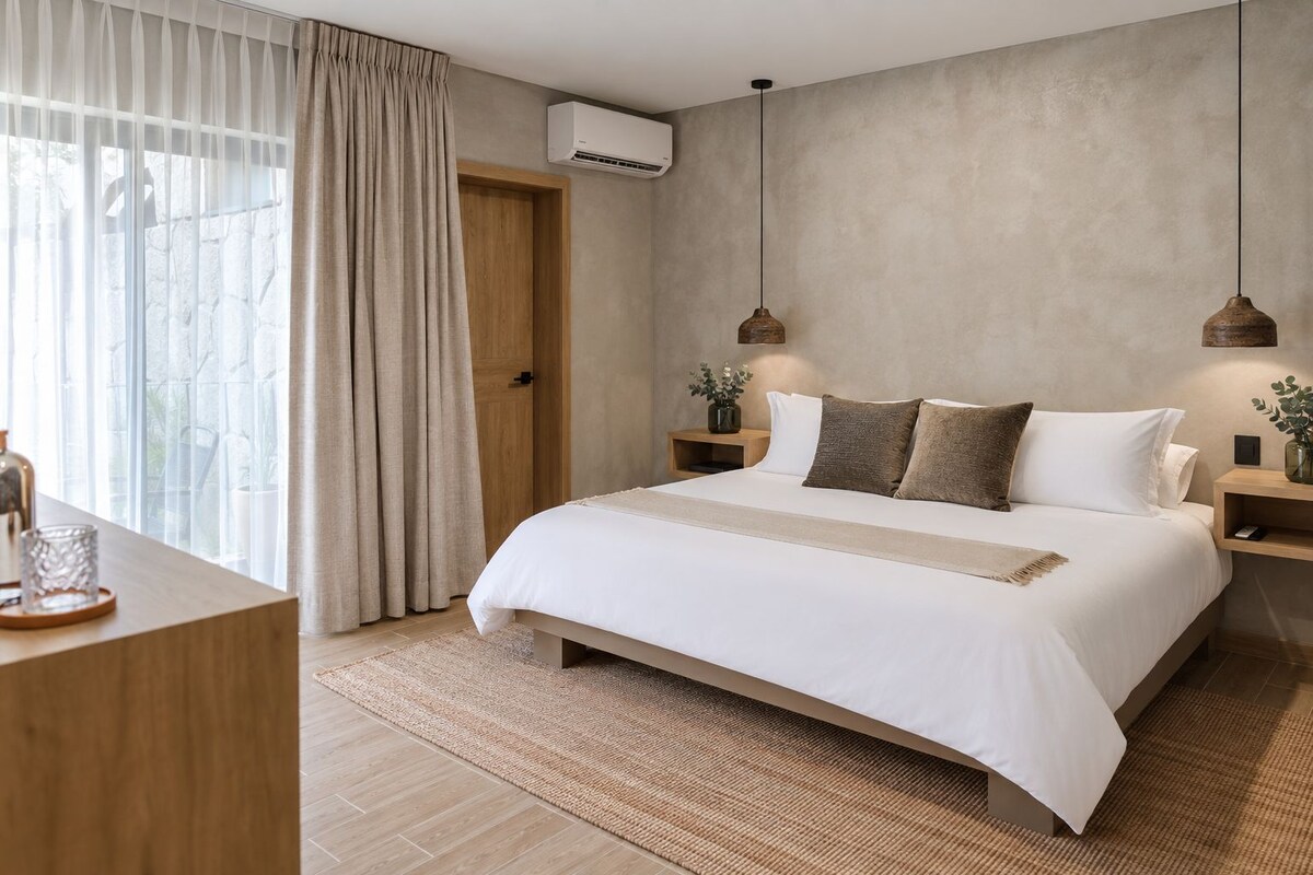 Quarto moderno com uma cama grande, mesa de cabeceira, ar condicionado e vista para o exterior.