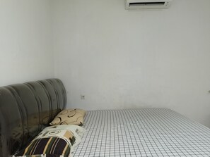 Quarto com cama, cabeceira, ar-condicionado fixado na parede e tomada.