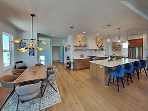 Cozinha moderna com ilha central, piso de madeira e iluminação pendente.