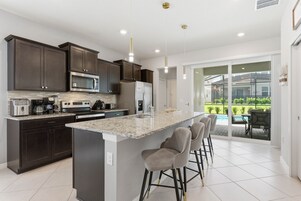 Uma cozinha moderna com armários escuros, eletrodomésticos de aço inoxidável e uma ilha grande com banquetas.