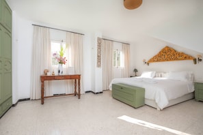 Quarto com cama, mesas de cabeceira, escrivaninha e cortinas.
