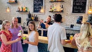Uma área de bar com um menu em lousa, garrafas de bebidas alcoólicas e uma câmera registrando a cena.