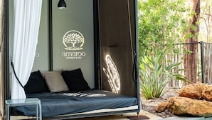 Uma área de estar moderna ao ar livre, com piscina, cama com almofadas e o logotipo de 'amargo RETREAT & SPA'.
