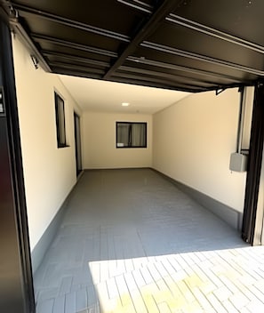 Um espaço interior com teto inclinado, uma pequena janela e uma porta.