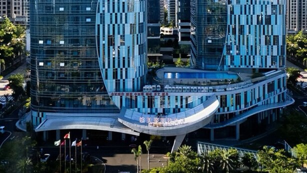 Um edifício moderno com fachadas de vidro curvo e um pátio central.