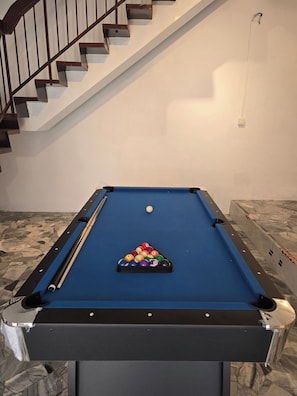 Uma mesa de bilhar com bolas, uma escadaria e um chão de mármore.