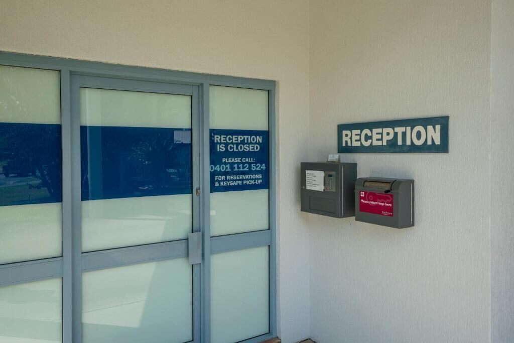 Uma área de recepção com placa de 'fechado', um telefone e um cofre para chaves.