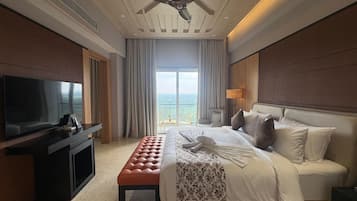 Quarto de hotel com televisão de tela plana, cama com dossel, ventilador de teto e vista para o exterior.