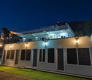 Um edifício de vários andares com varanda, janelas amplas e fachada bem iluminada.