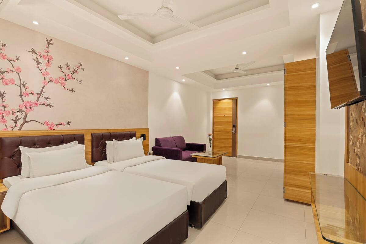 Quarto de hotel moderno com uma cama grande, um sofá, uma pequena mesa e um guarda-roupa de madeira.