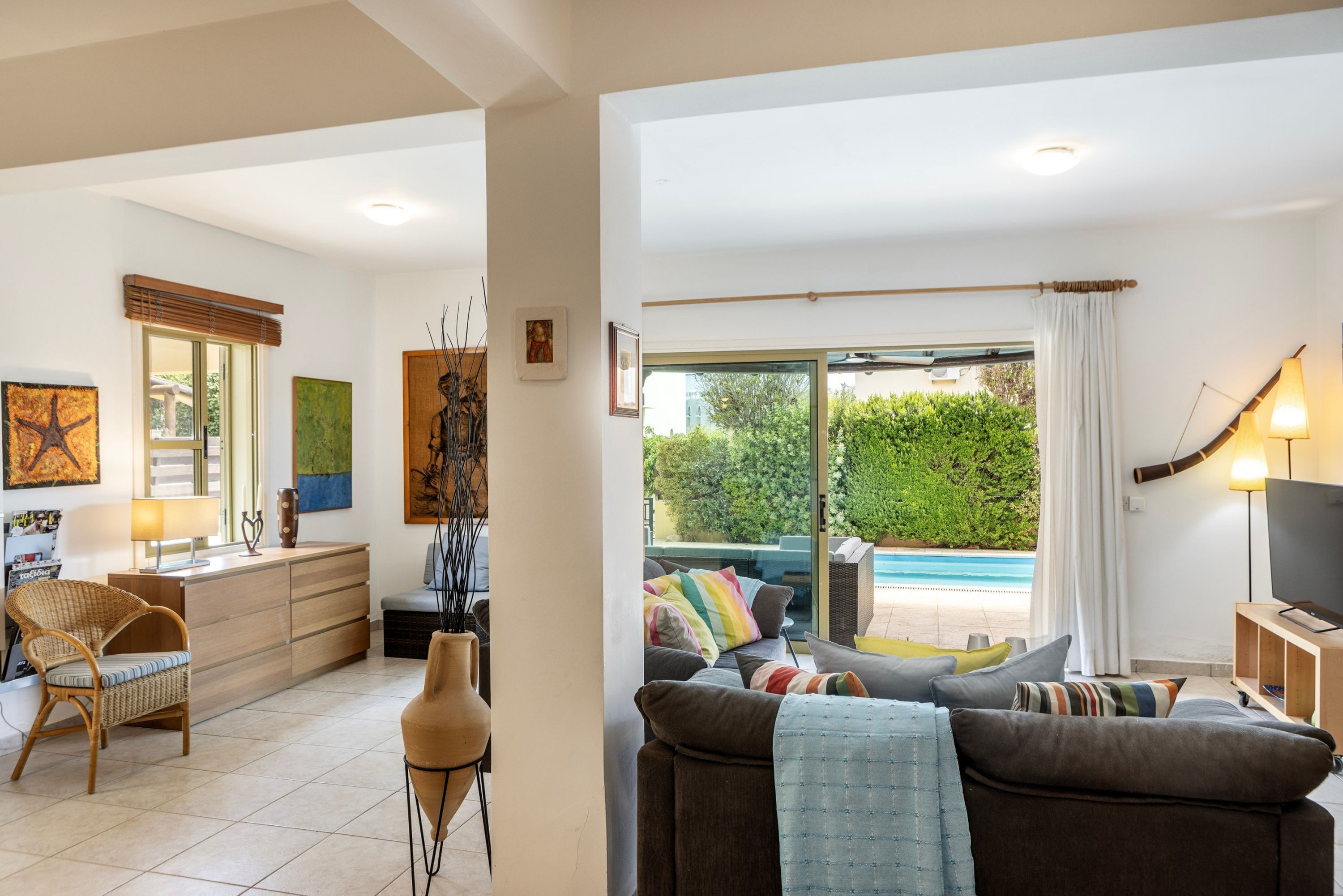 Sala de estar com sofá, poltrona, televisão e vista para a piscina.