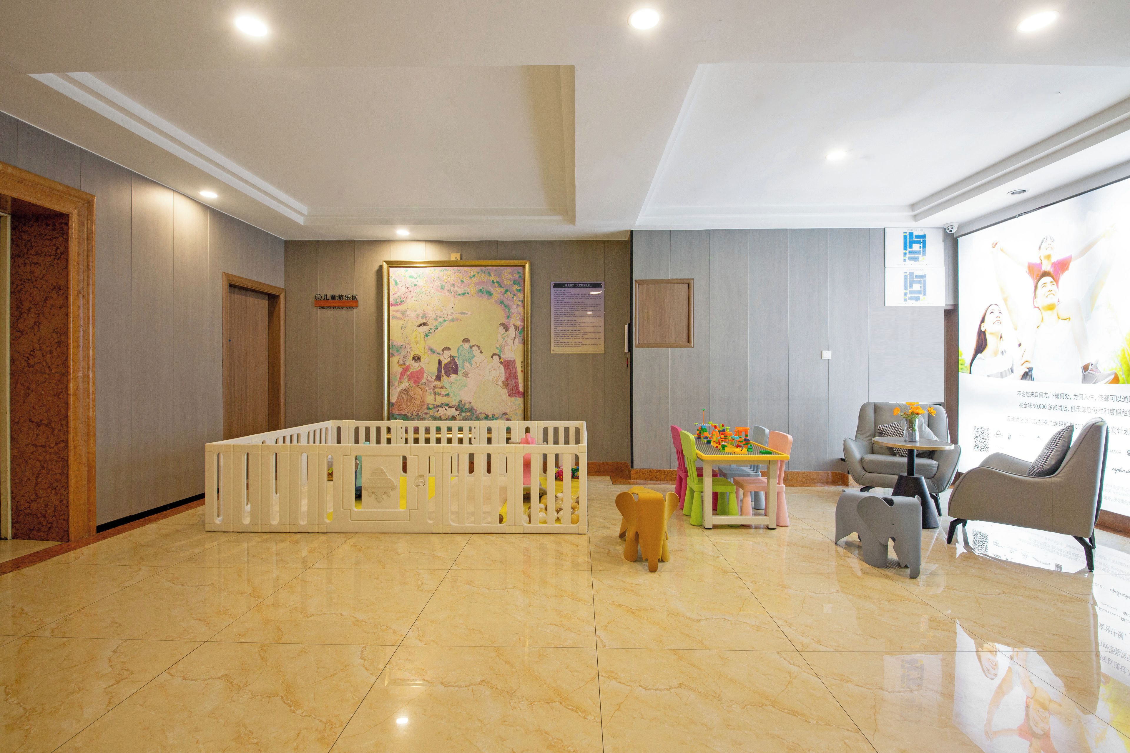 Espaço de recreação infantil com uma pintura grande, cercadinho e brinquedos coloridos.