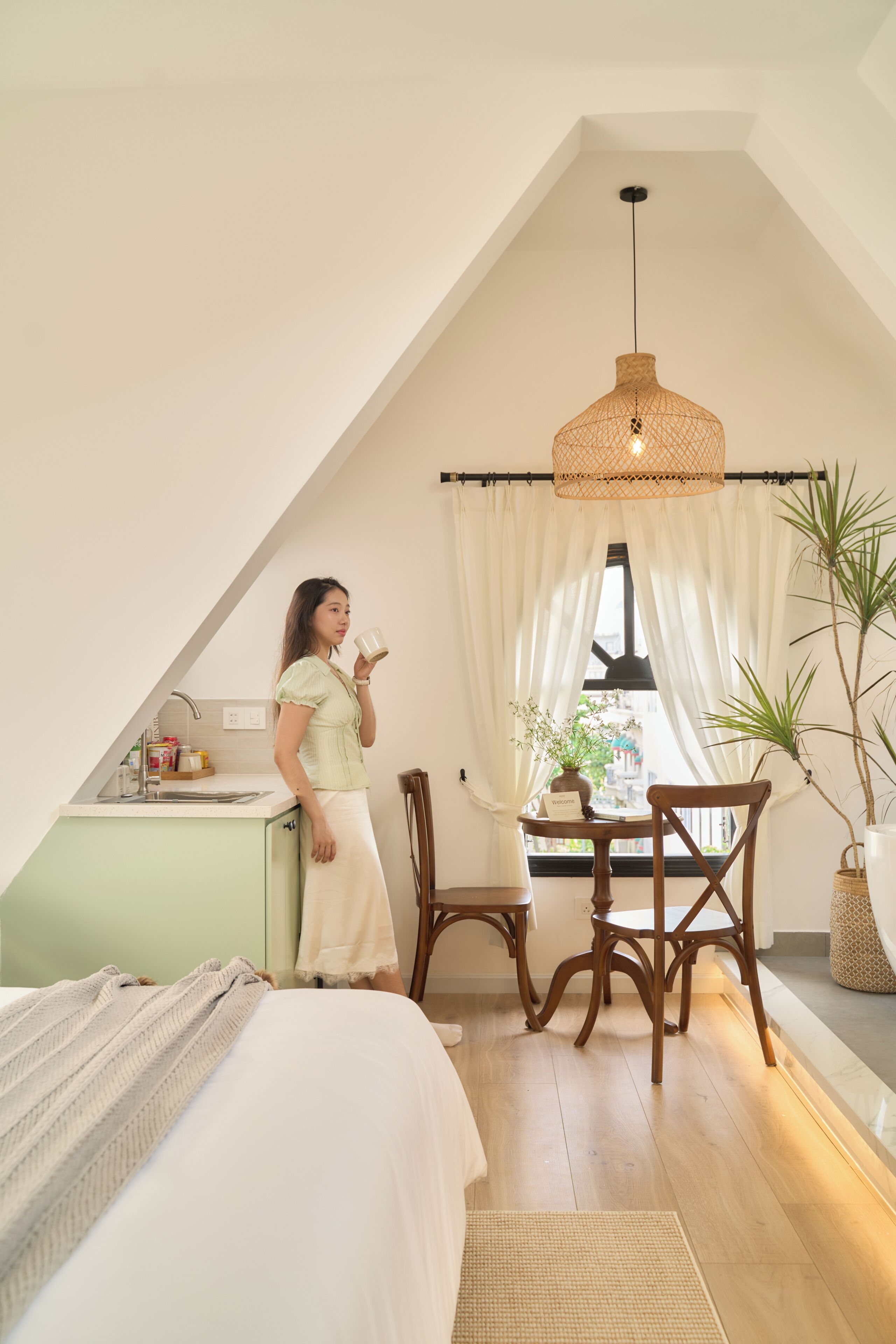 Um quarto acolhedor com teto inclinado, área de jantar com mesa e cadeiras, luminária pendente e vista pela janela.
