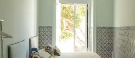 Quarto com duas camas, uma janela e parede com padrão.