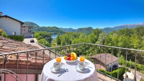 Varanda com mesa posta para o café da manhã, com vista para uma paisagem montanhosa.