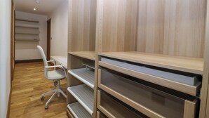 Um quarto com piso de madeira, uma cadeira de escritório branca e estantes embutidas.