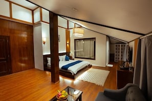 Quarto com cama, mesa de cabeceira e vista para o exterior.