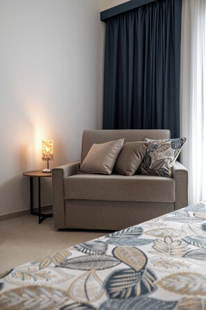 Quarto moderno com sofá, luminária e colcha estampada.