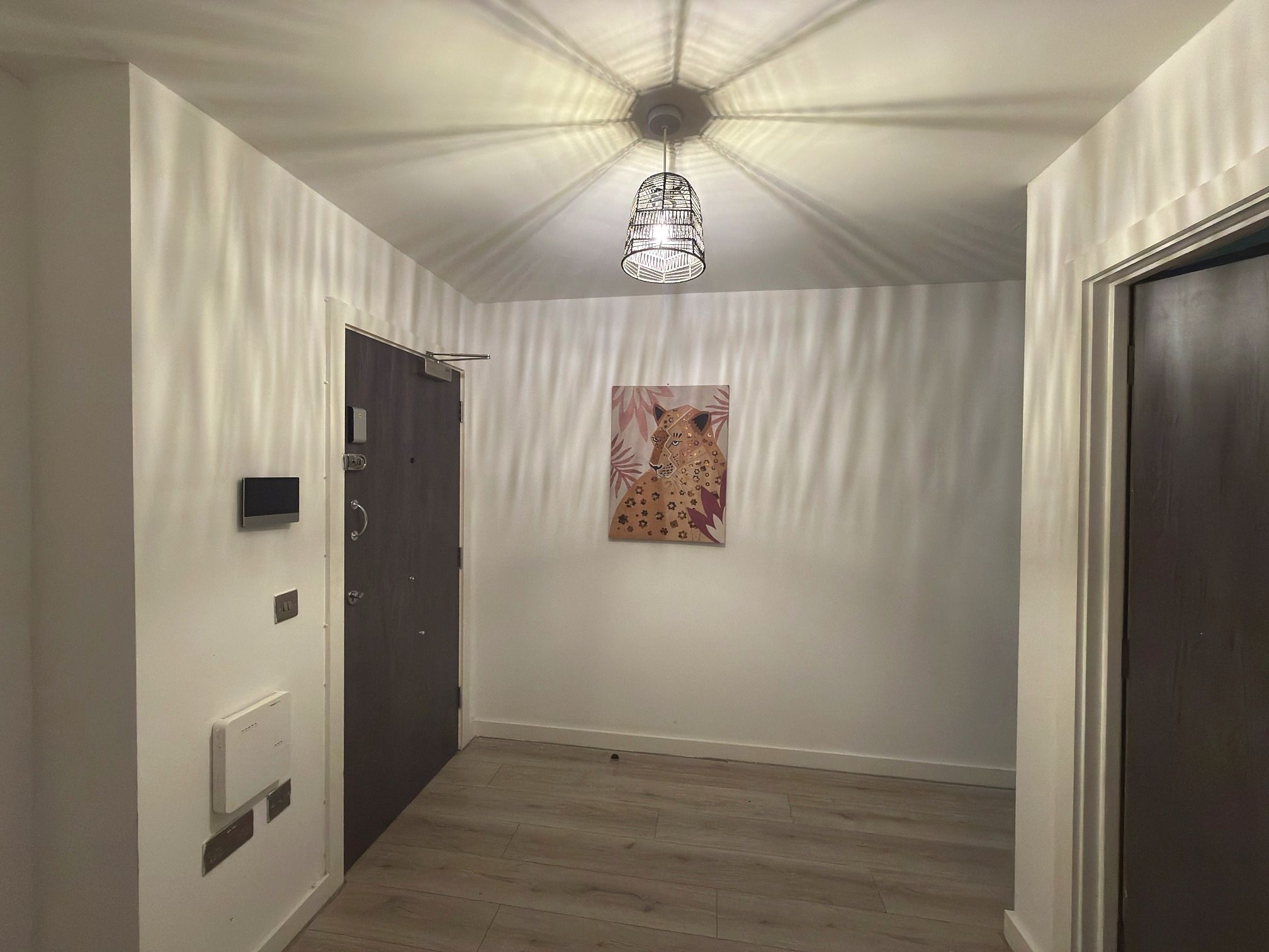 Um corredor com ventilador de teto, porta com porta-toalhas, luminária na parede e quadro pendurado.