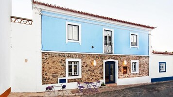 Um edifício de dois andares com fachada de pedra, seção superior azul e telhado em telhas.