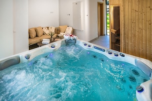Uma banheira de hidromassagem em um quarto com sofá e paredes de madeira.
