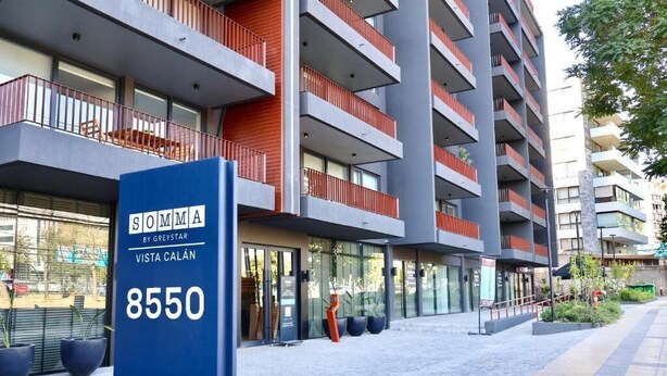 Um edifício moderno com varandas, uma placa azul com o número 8550 e uma entrada de vidro.