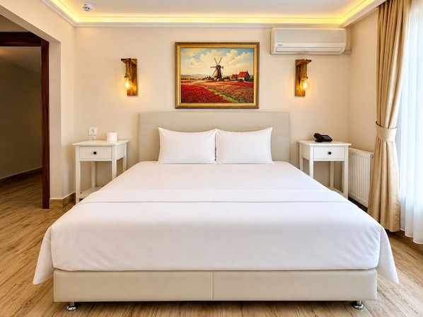 Quarto de hotel com uma cama grande, duas mesas de cabeceira, um quadro de um moinho de vento e um aparelho de ar condicionado.