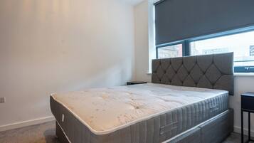 Quarto com cama, janela com cortina e vista para a cidade.
