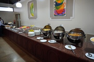 Disposição de buffet com diversos alimentos e utensílios de servir.