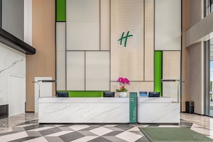 Bancada de recepção de hotel com design moderno, destacando-se por um balcão de mármore, uma parede de destaque verde e placas indicando os serviços 'Diamond Elite' e 'Platinum Elite'.
