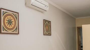 Quarto com duas camas, um ventilador de teto e dois aparelhos de ar condicionado na parede.