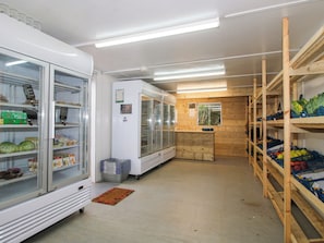 Interior de um supermercado com balcões refrigerados, prateleiras de madeira e um caixa de atendimento.