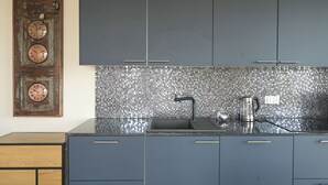 Uma cozinha com painel de azulejos, pia e cafeteira.