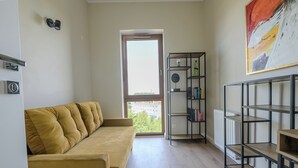 Sala de estar com sofá, estante, radiador e uma janela grande.