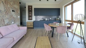 Uma cozinha moderna com armários escuros, uma mesa de jantar de madeira com cadeiras rosa, e uma janela grande que proporciona luz natural.
