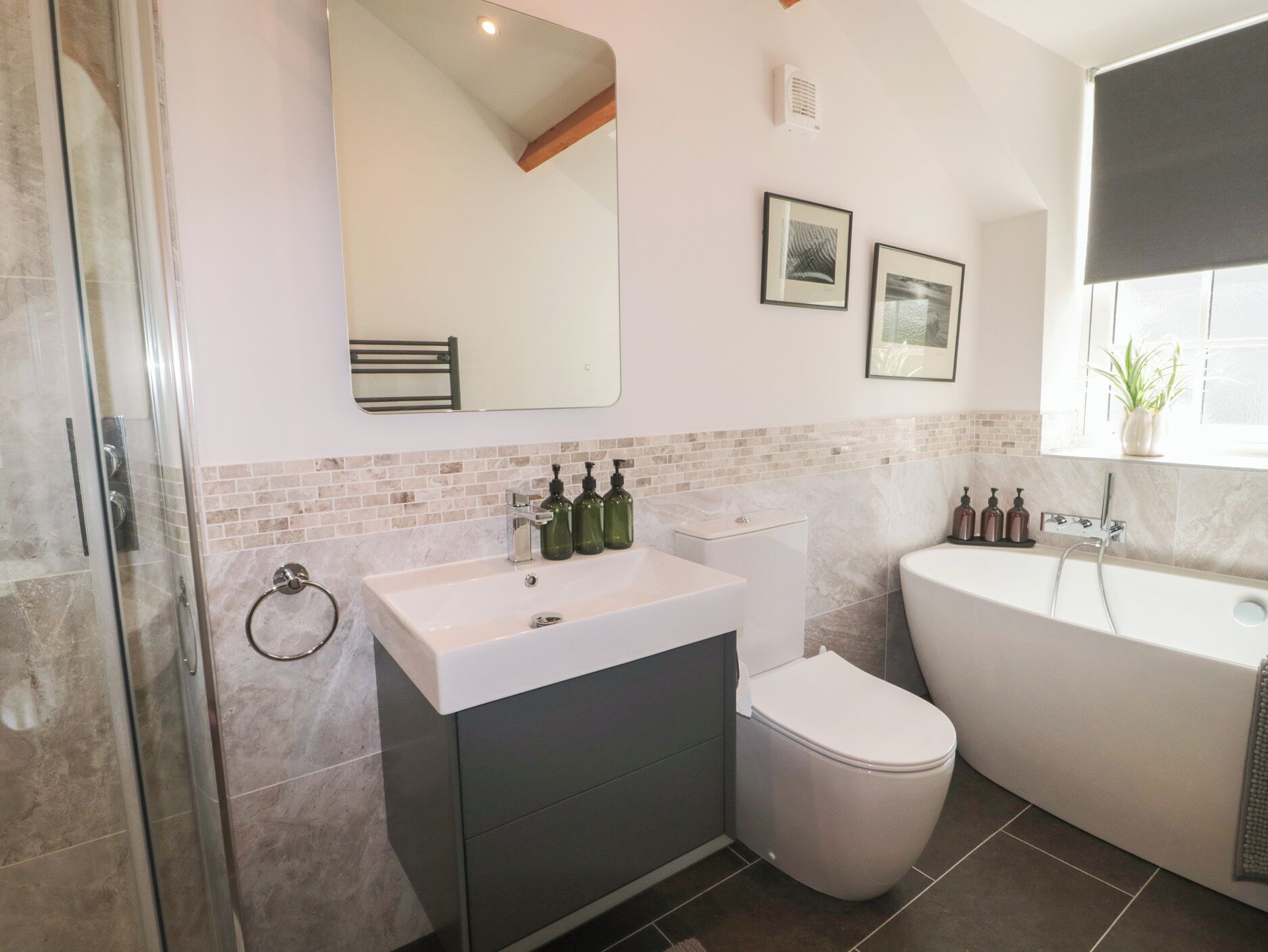 Uma casa de banho moderna com cabine de duche em vidro, lavatório branco com dispensadores de sabonete verde, sanita branca e banheira branca.