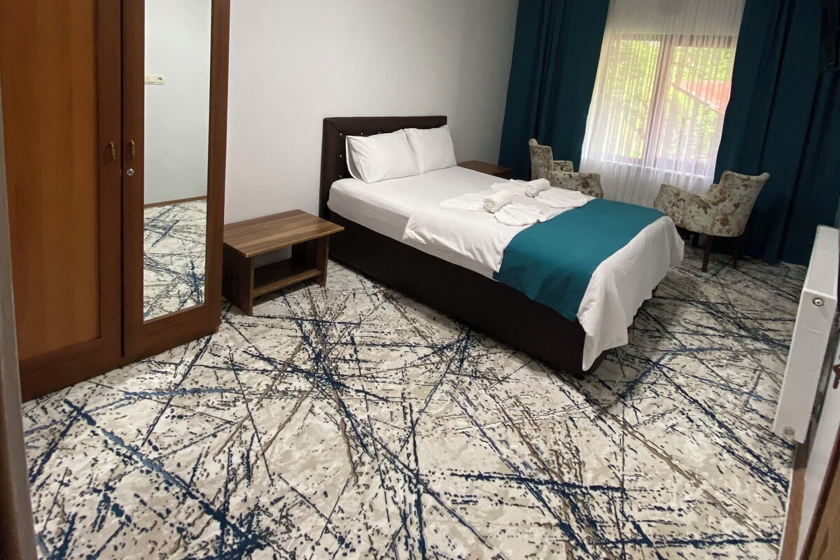Quarto com cama, espelho, guarda-roupa e luminária no teto.