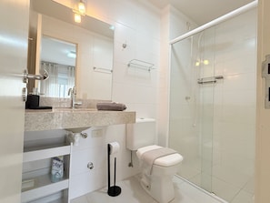 Uma casa de banho moderna com cabine de chuveiro em vidro, sanita e lavatório com espelho.