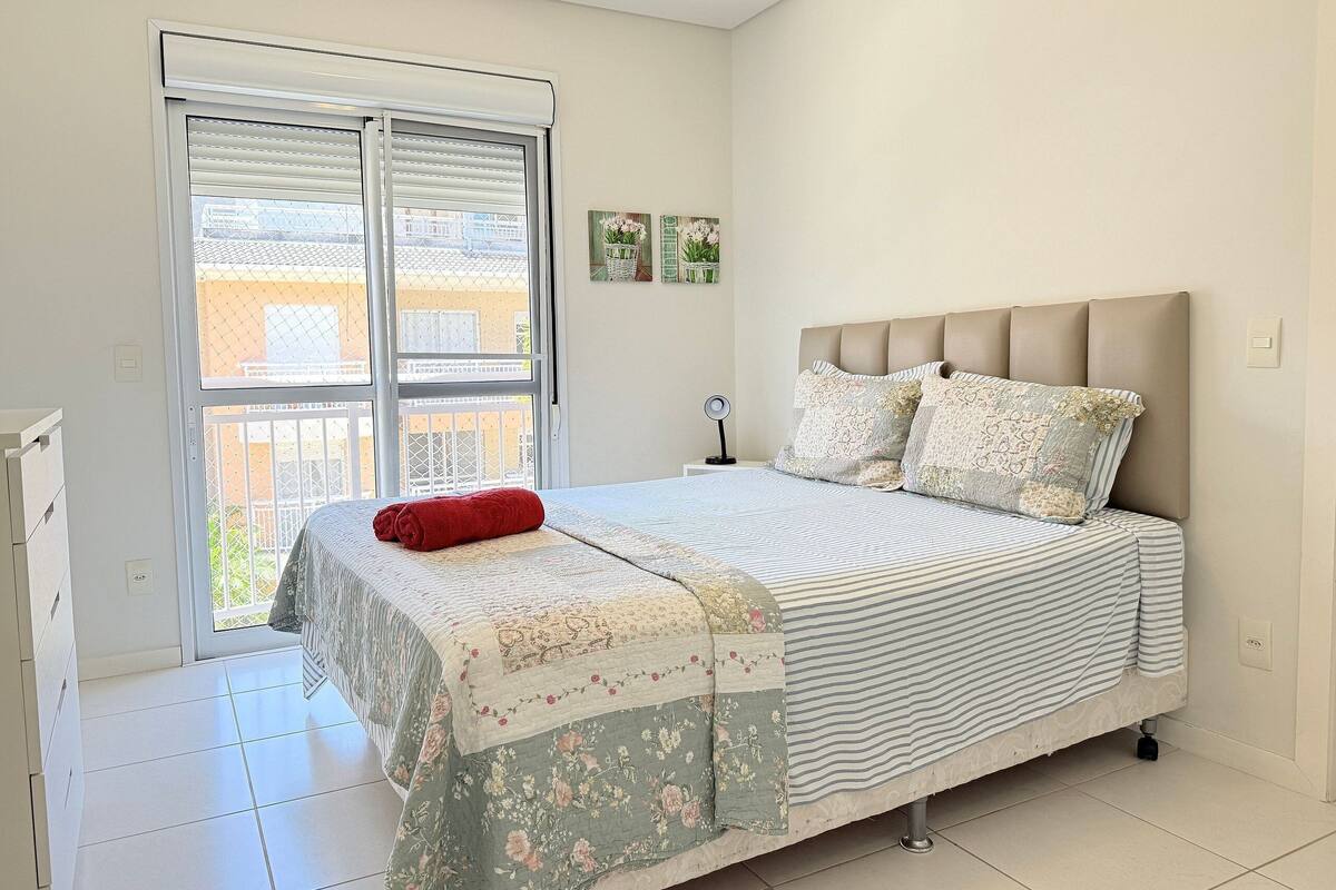 Quarto com cama, janela e vista para edifícios.