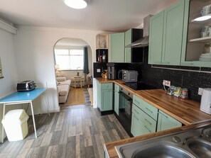 Uma cozinha compacta com bancada de madeira, micro-ondas e pia.