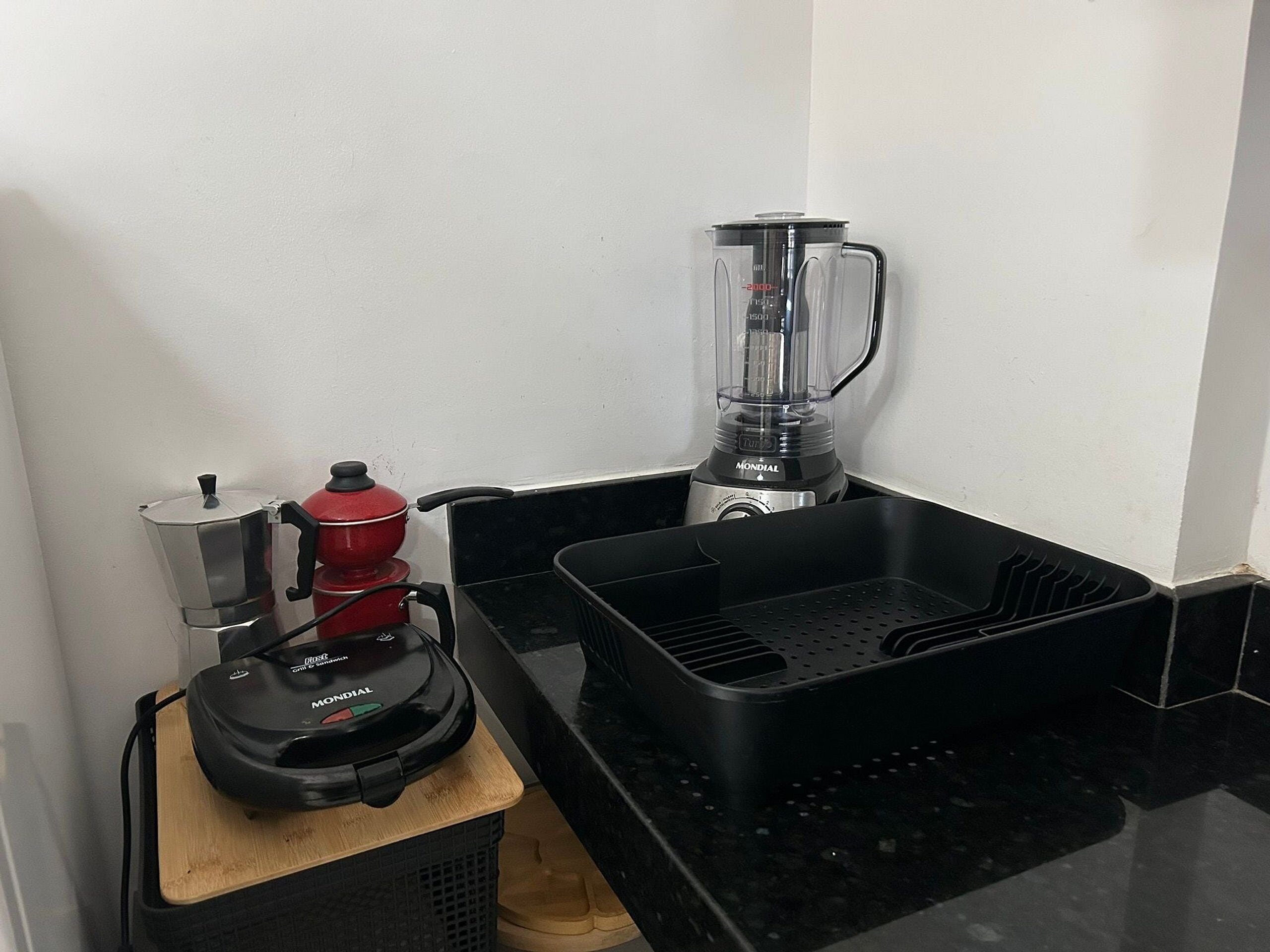 Cozinha com cafeteira, liquidificador e bandeja preta.