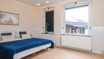 Quarto com cama, janela, radiador e um quadro na parede.