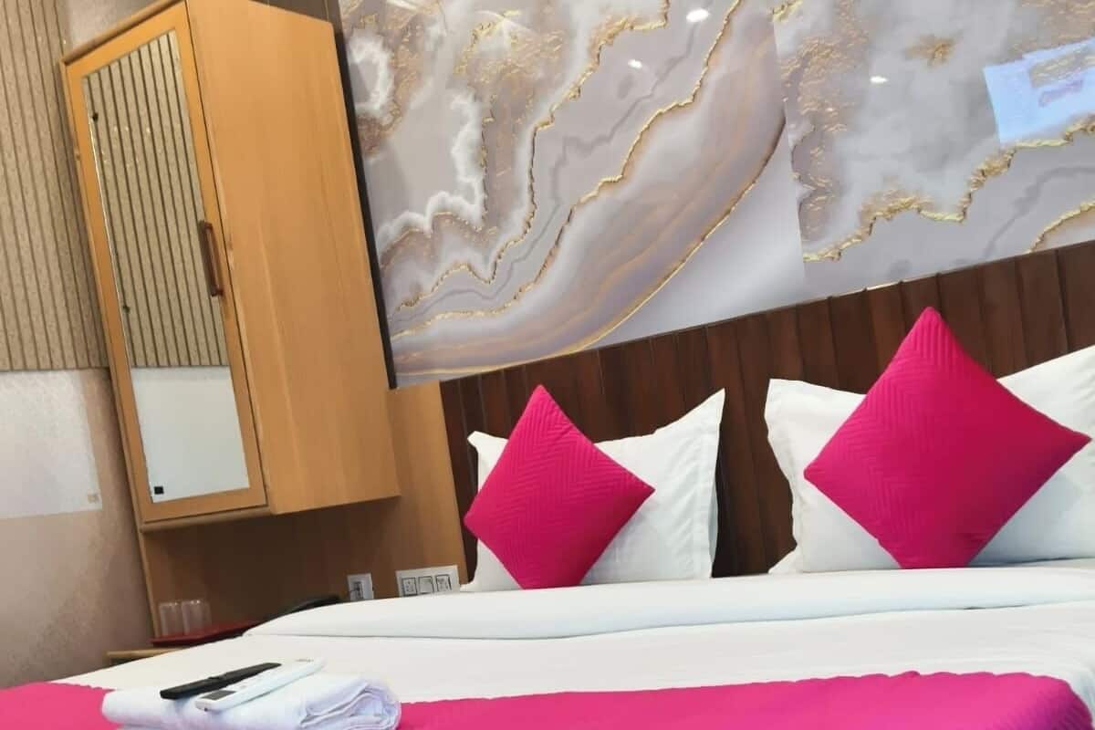Quarto de hotel com cama, guarda-roupa de madeira e parede de mármore.